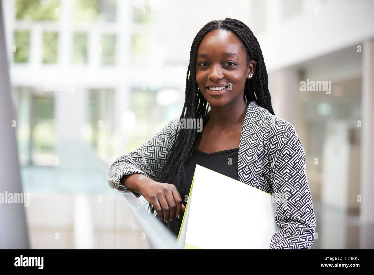 Smiling young black female student in university foyer Stock Photo - Alamy