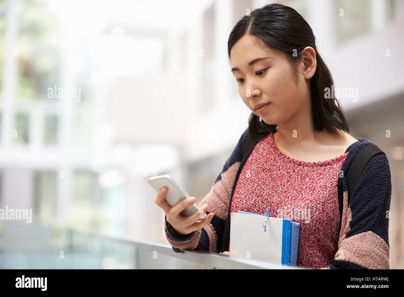 Asian female adult student using phone in university lobby Stock Photo ...