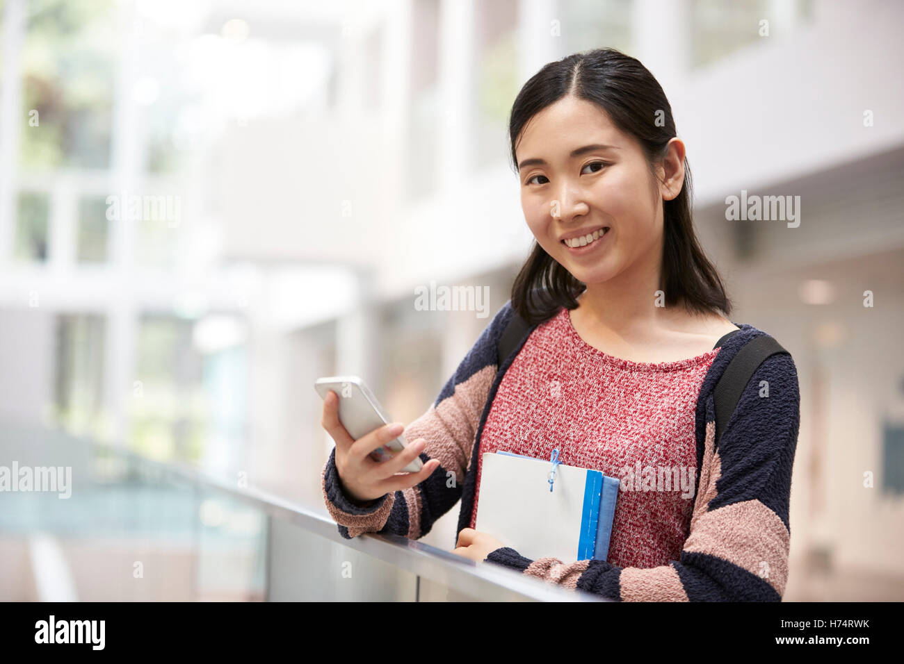 Asian female adult student using phone looks to camera Stock Photo - Alamy