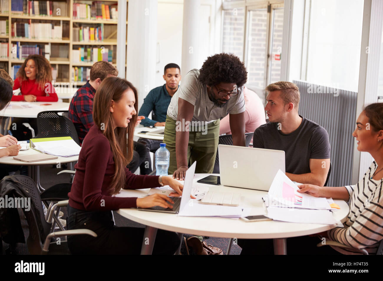 Busy University Library With Students And Tutor Stock Photo - Alamy