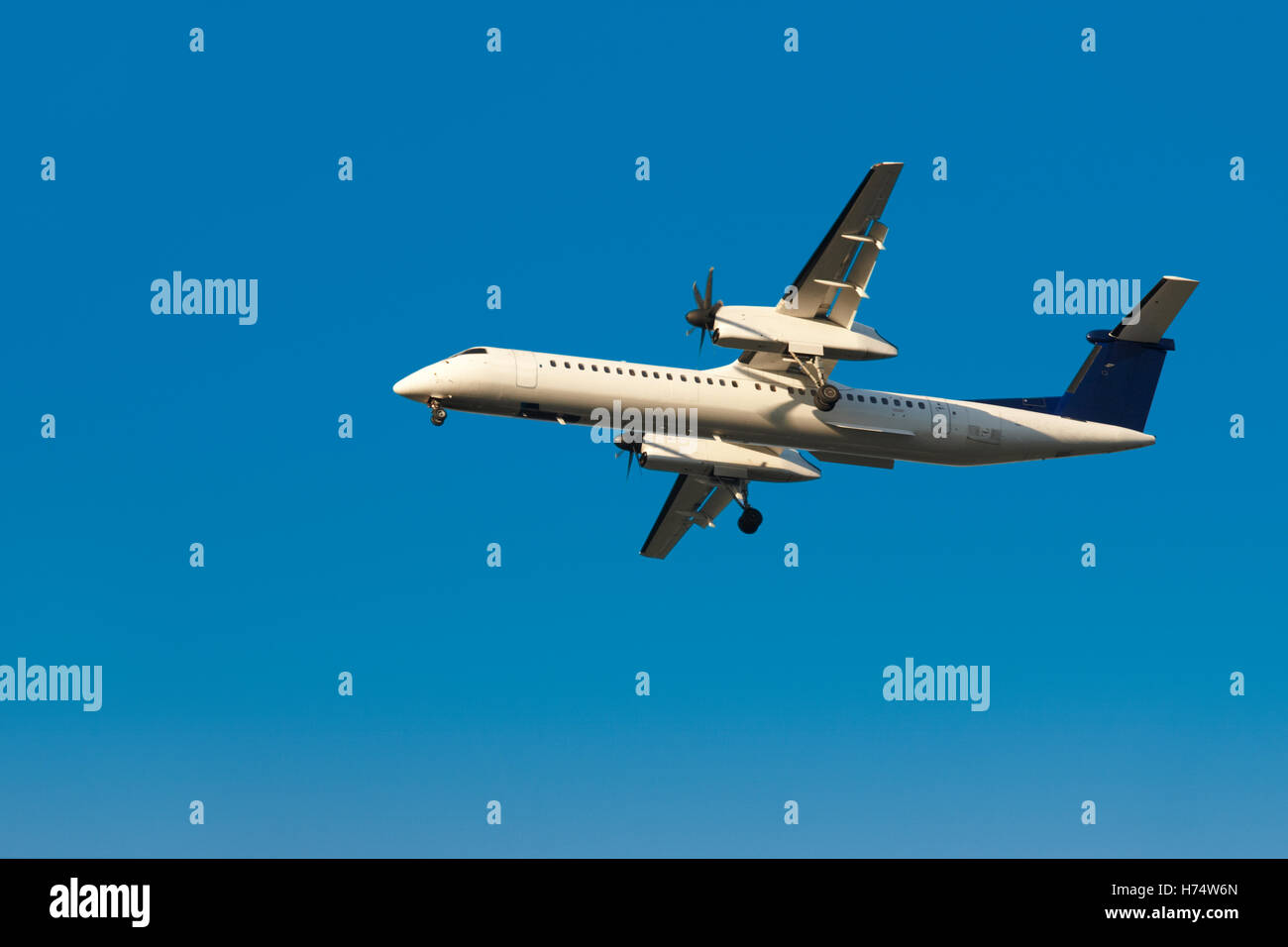 White airplane flying over a clean blue sky. Horizontal Stock Photo - Alamy