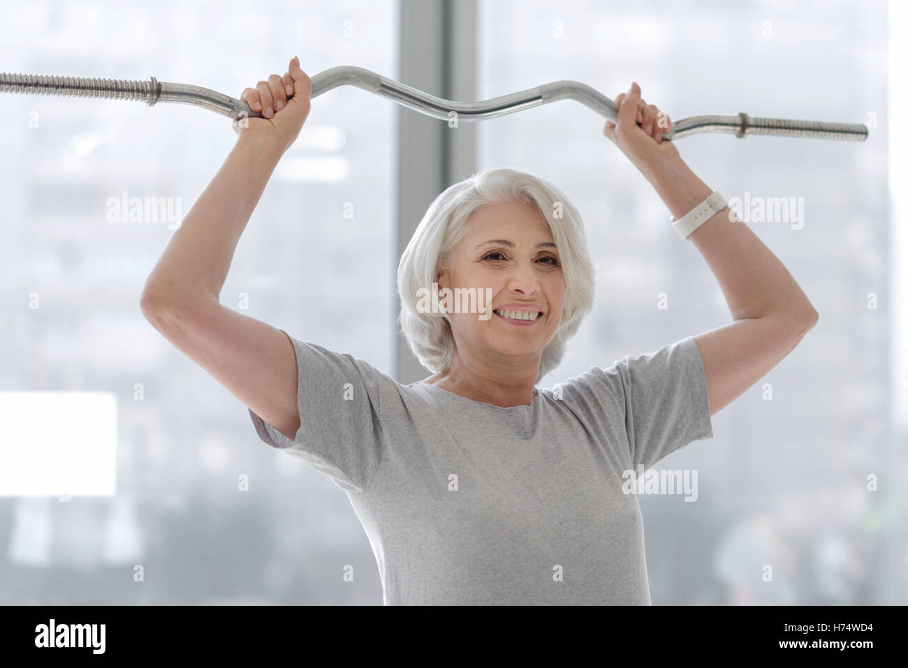 Active smiling woman lifting barbell Stock Photo - Alamy