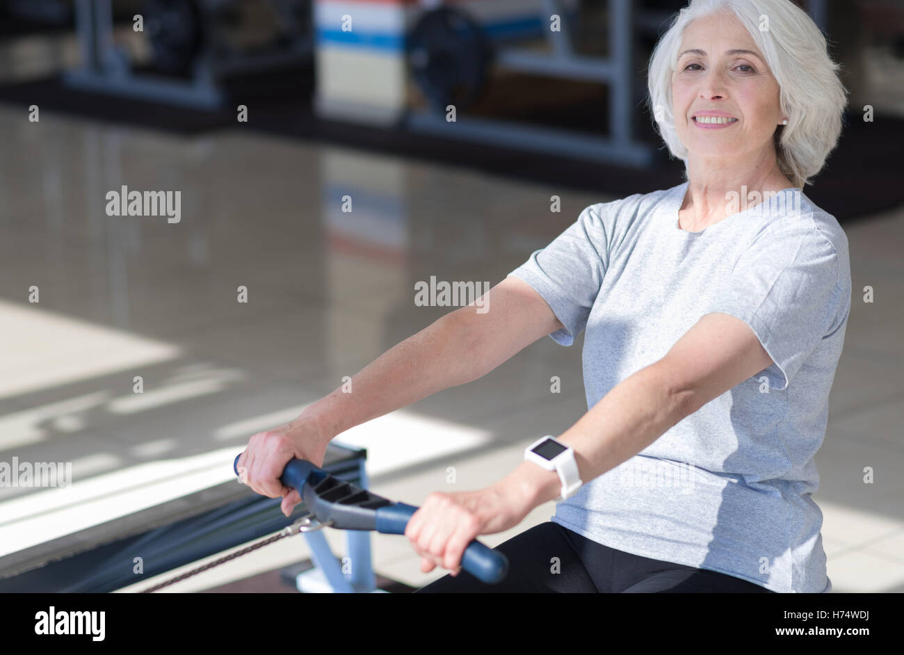 Laughing beautiful woman using rowing machine Stock Photo - Alamy