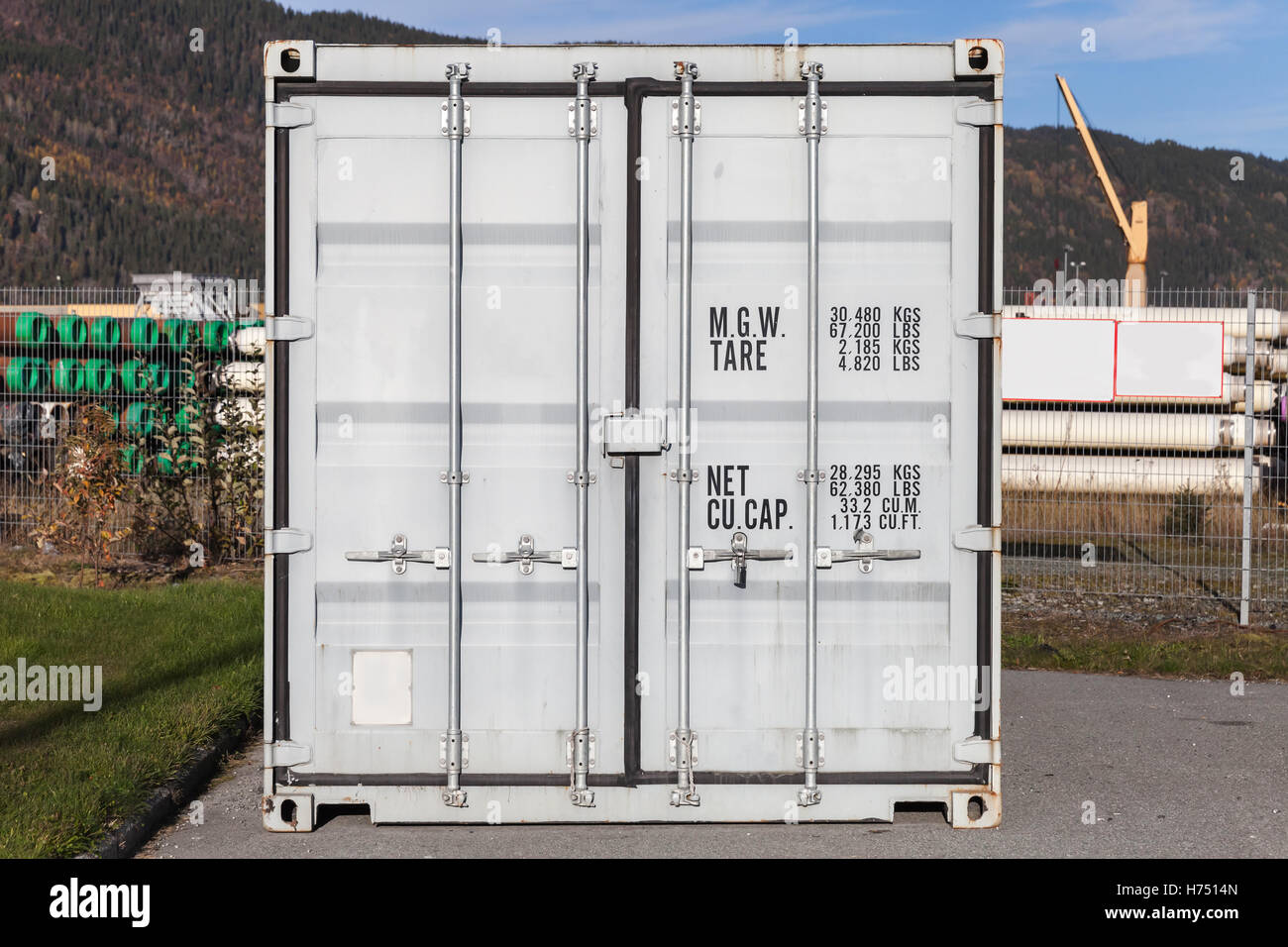 Closed white standard cargo container stands in port area, door face ...