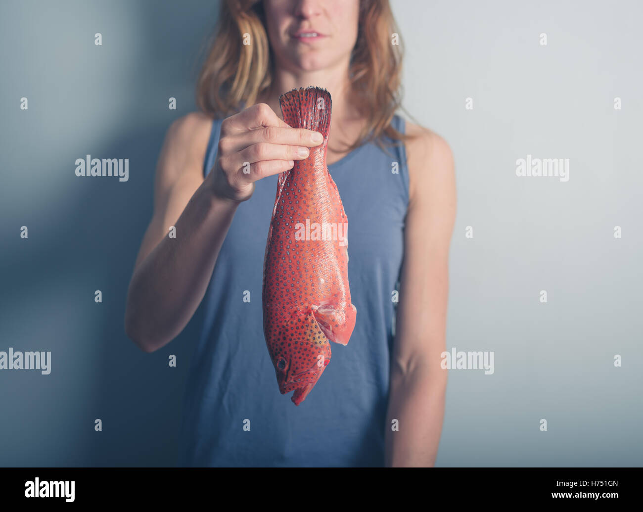 A young woman is holding a tropical red butterfish Stock Photo - Alamy