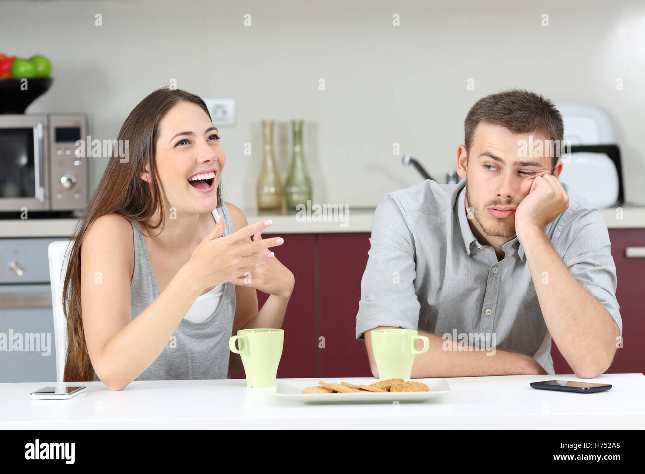 Bored husband hearing his wife talking during breakfast in the kitchen ...