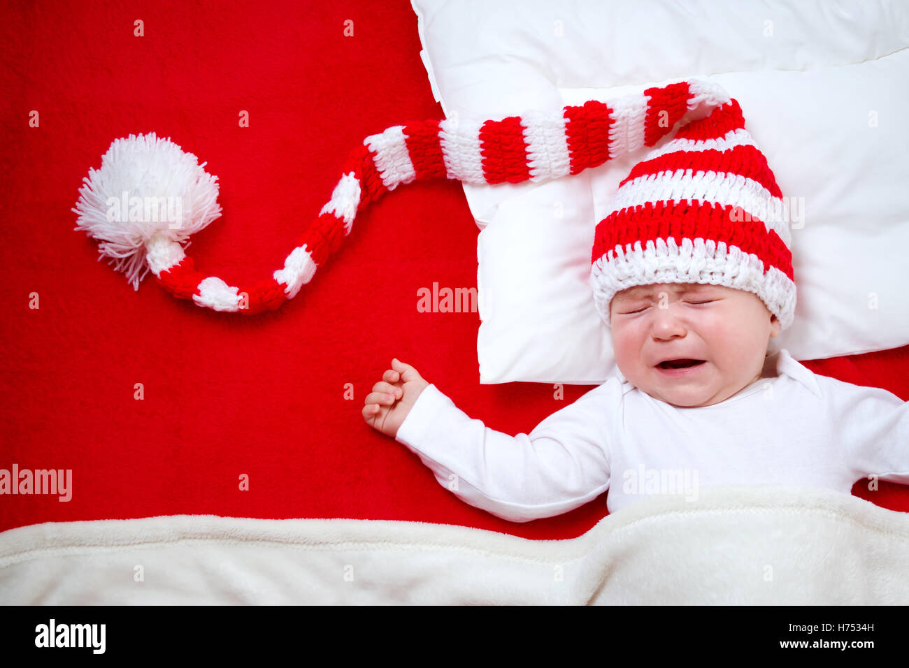 Sleepy baby on red blanket Stock Photo - Alamy