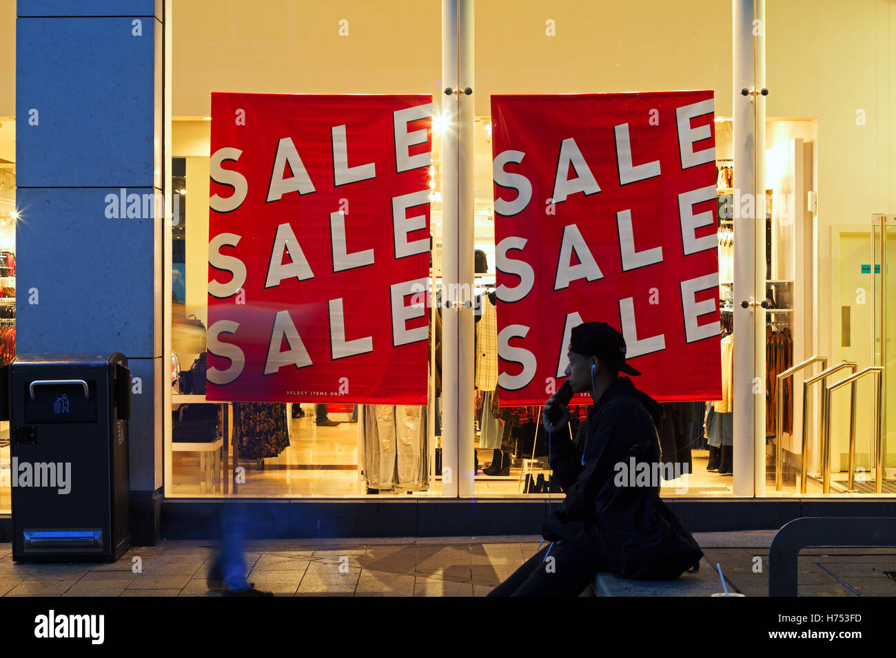 A man sitting outside a shop with a sale sign at night Stock Photo - Alamy