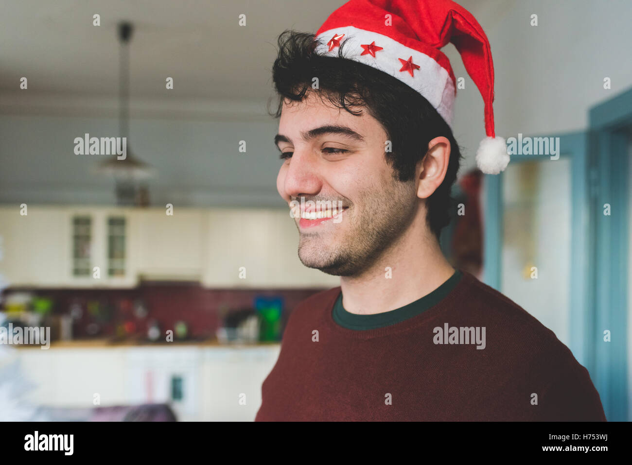 Half length of young handsome man wearing Santa Claus hat indoor in ...