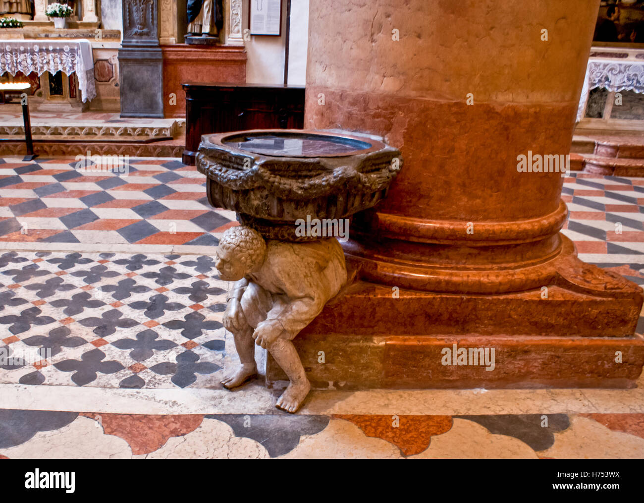 the aspersorium with holy water in the form of a hunched man in church ...