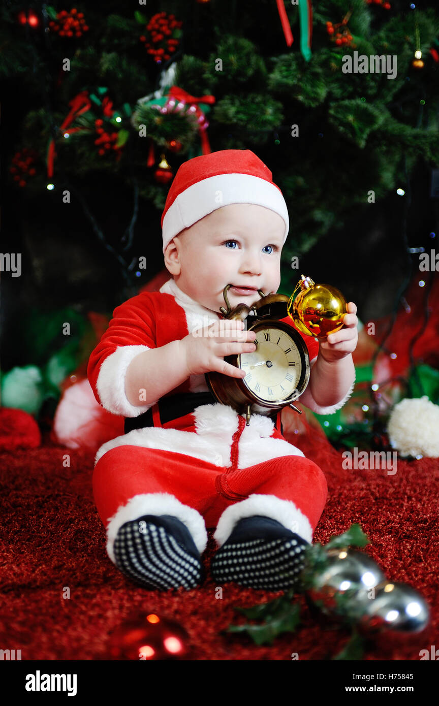 Child dressed as Santa Claus gnawing teeth clock alarm . Ch Stock Photo ...