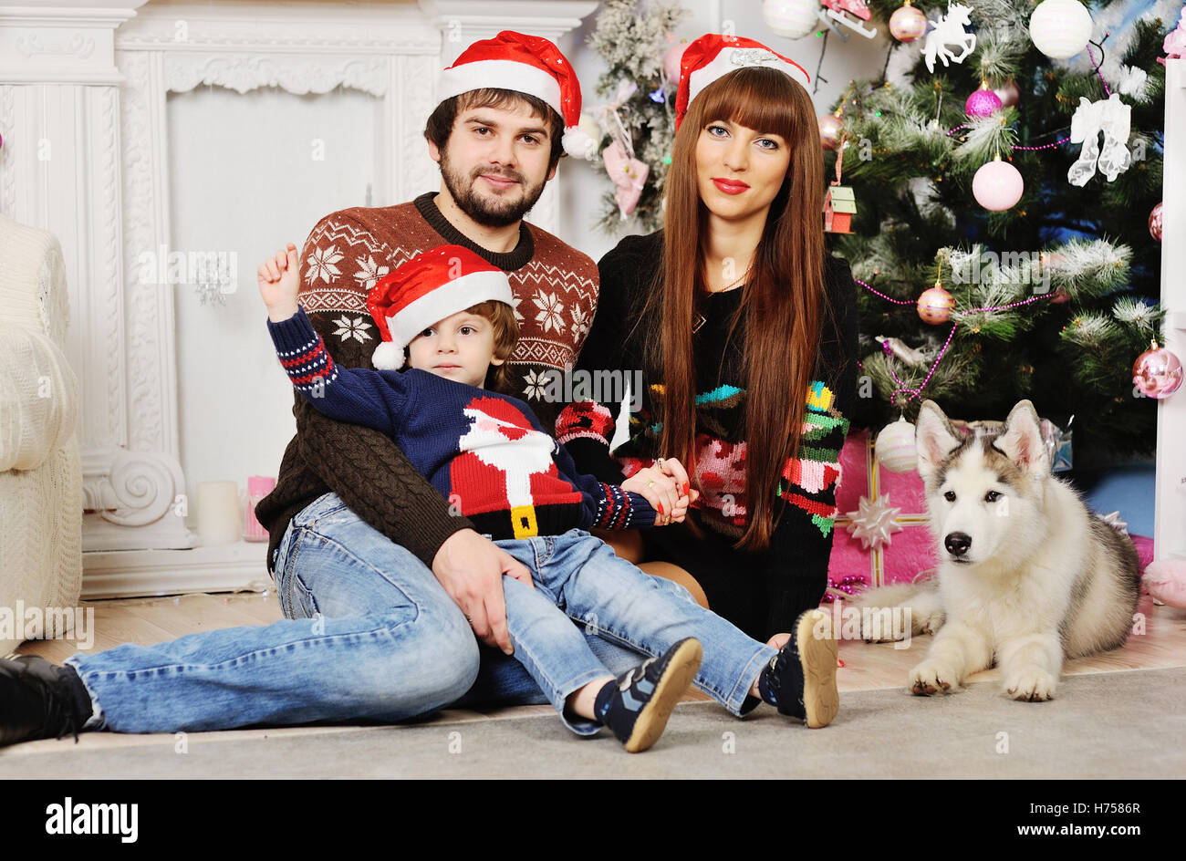 young family sitting under the Christmas tree Stock Photo - Alamy