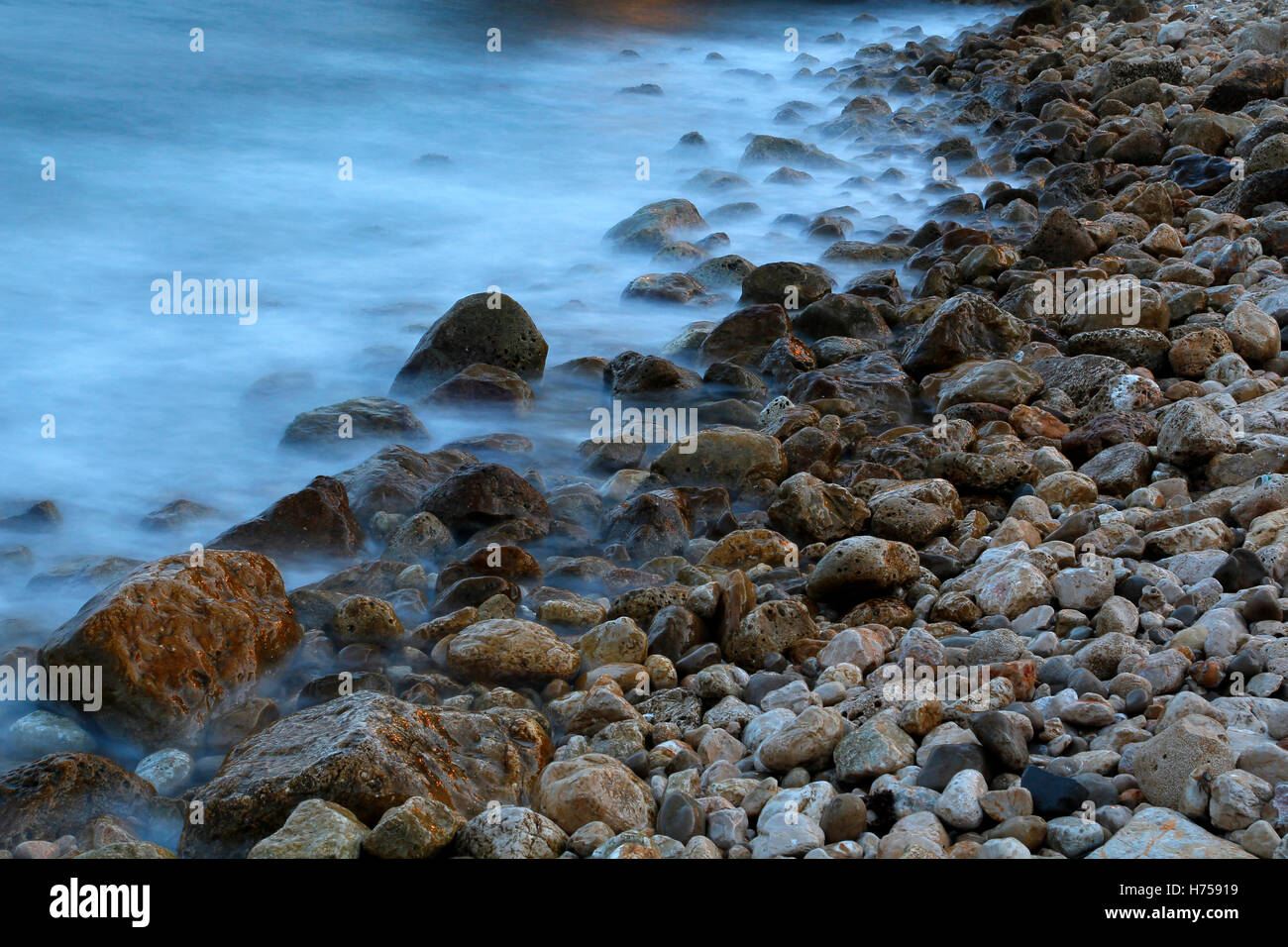 Seashore with stones in a long exposure shot Stock Photo - Alamy