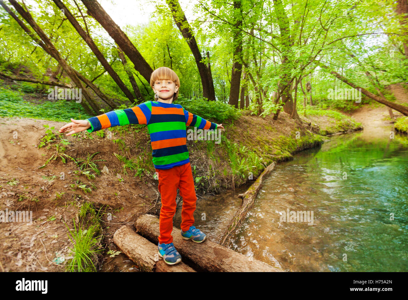 Cute boy balancing on a log bridge over the river Stock Photo - Alamy
