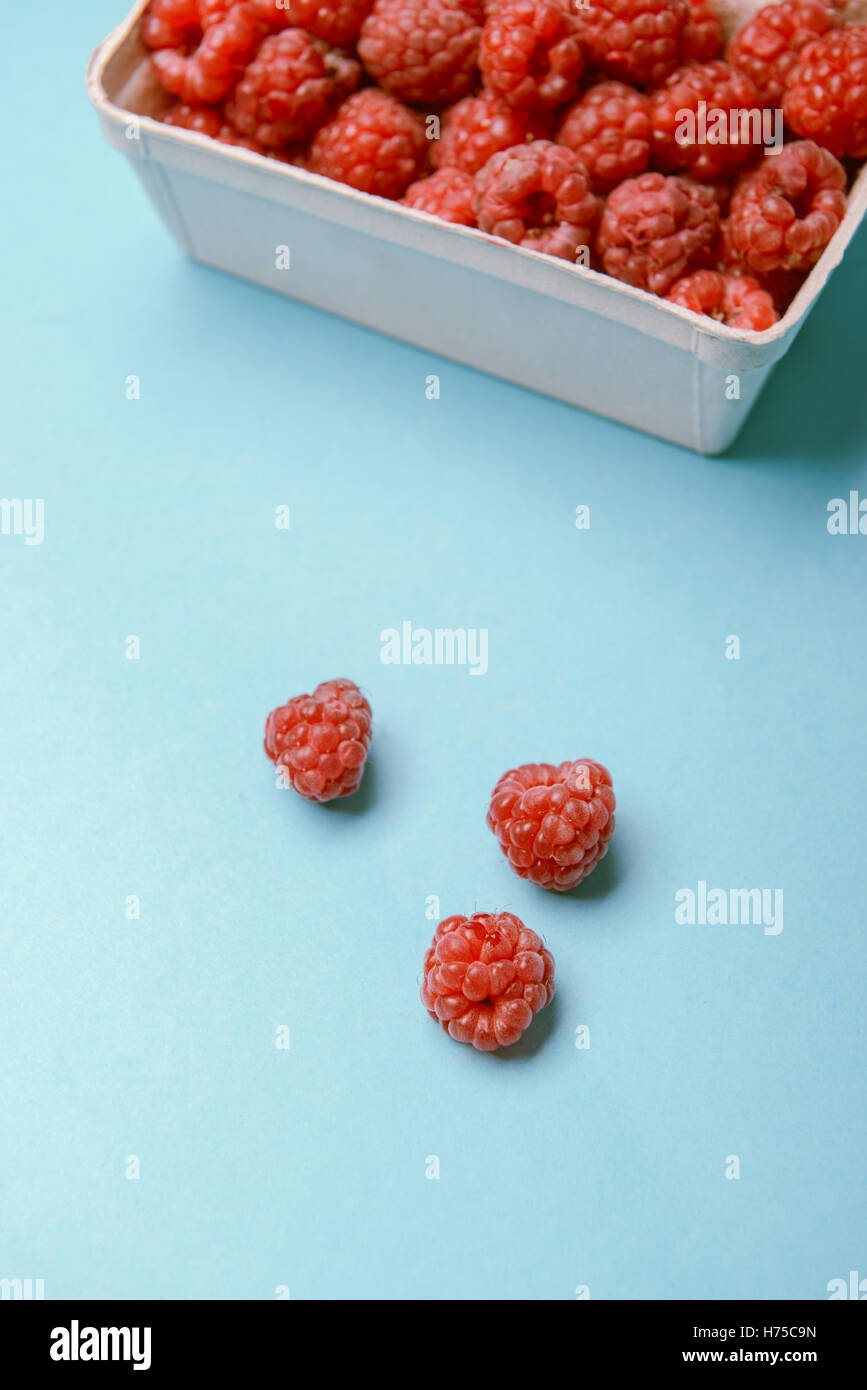 box of fresh raspberries on a blue background Stock Photo - Alamy
