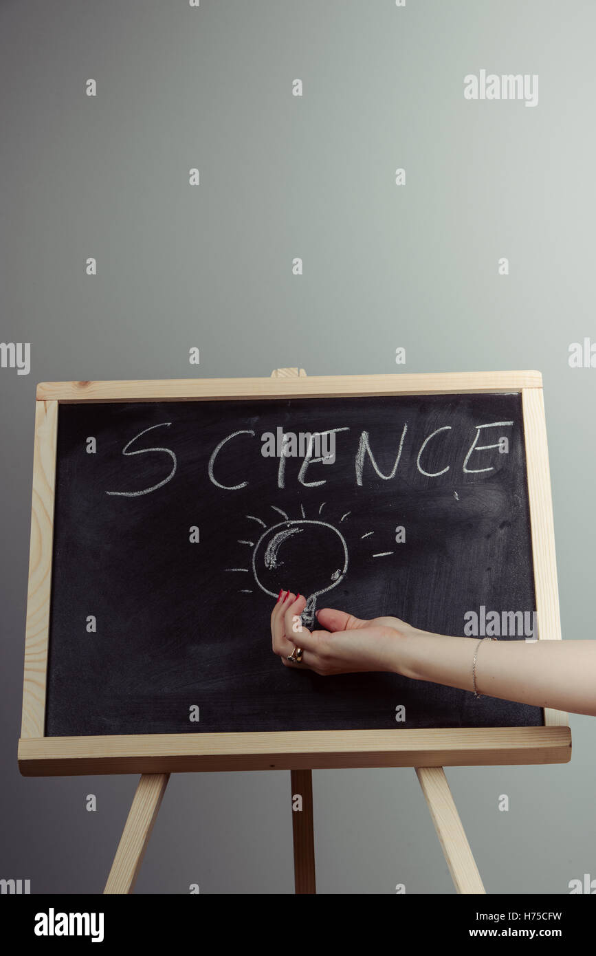 A teacher writing science, drawing chemistry elements on dark ...