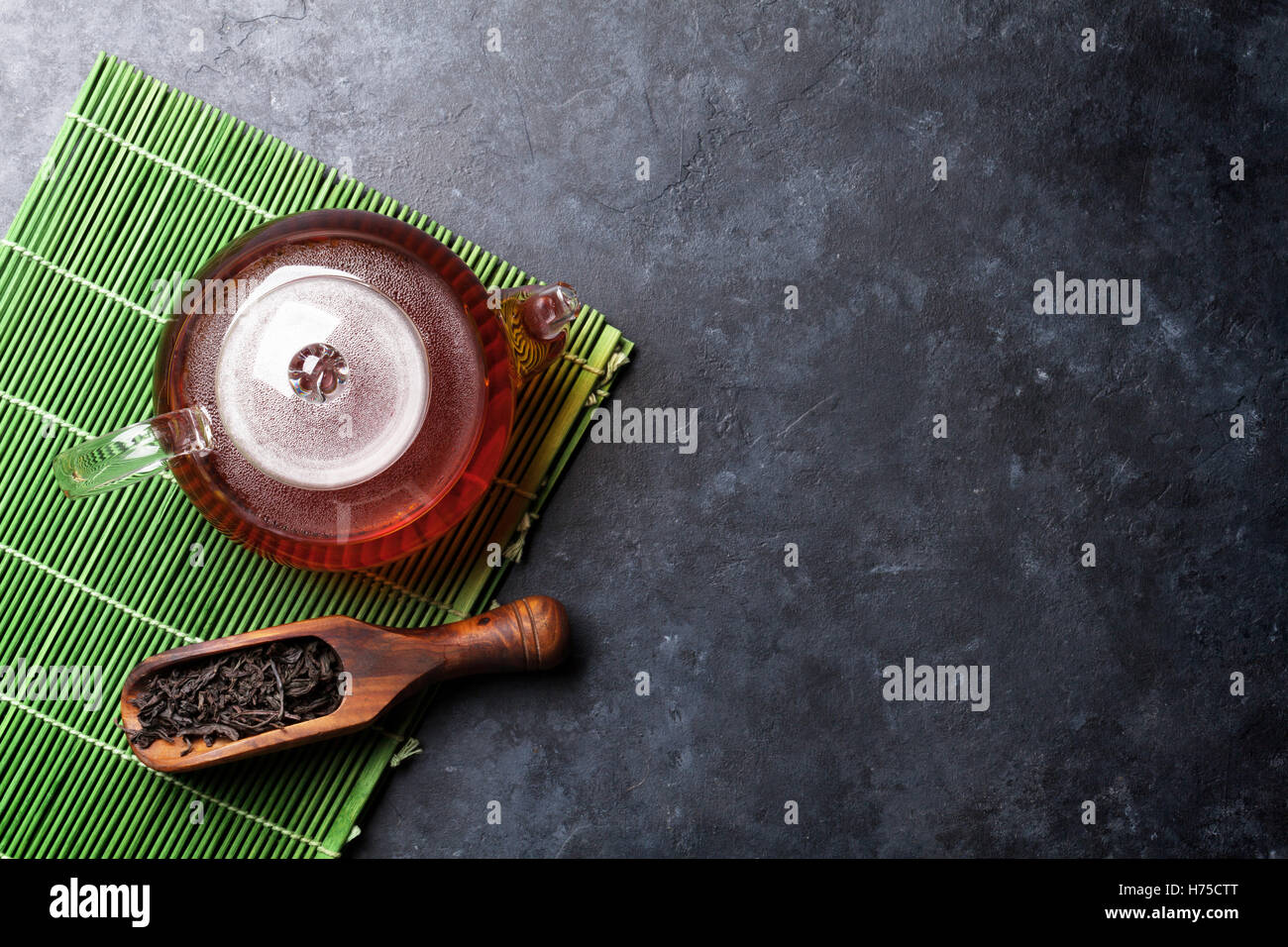 Teapot and dry tea in spoon on stone table. Top view with copy space ...