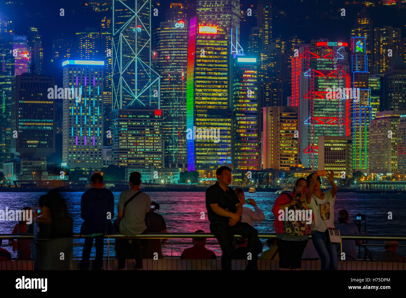 The famous Tsim Sha Tsui promenade, and tourists enjoying the evening view of Hong Kong Island ...