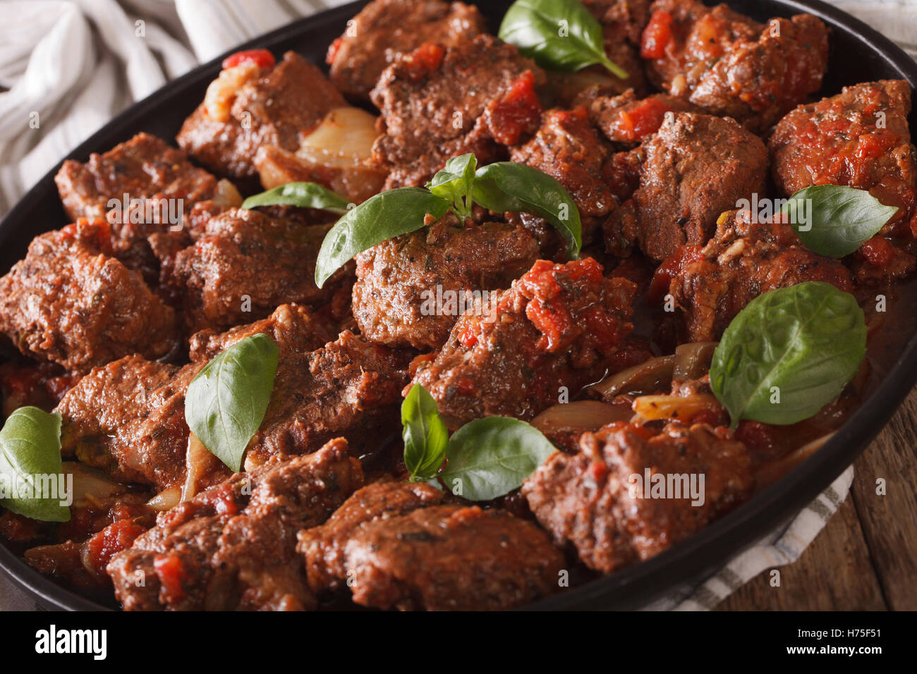 Greek stifado beef with sauce and basil macro on the plate. horizontal ...