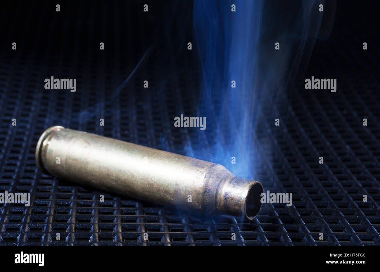 Empty rifle cartridge on a black grate with smoke around Stock Photo ...