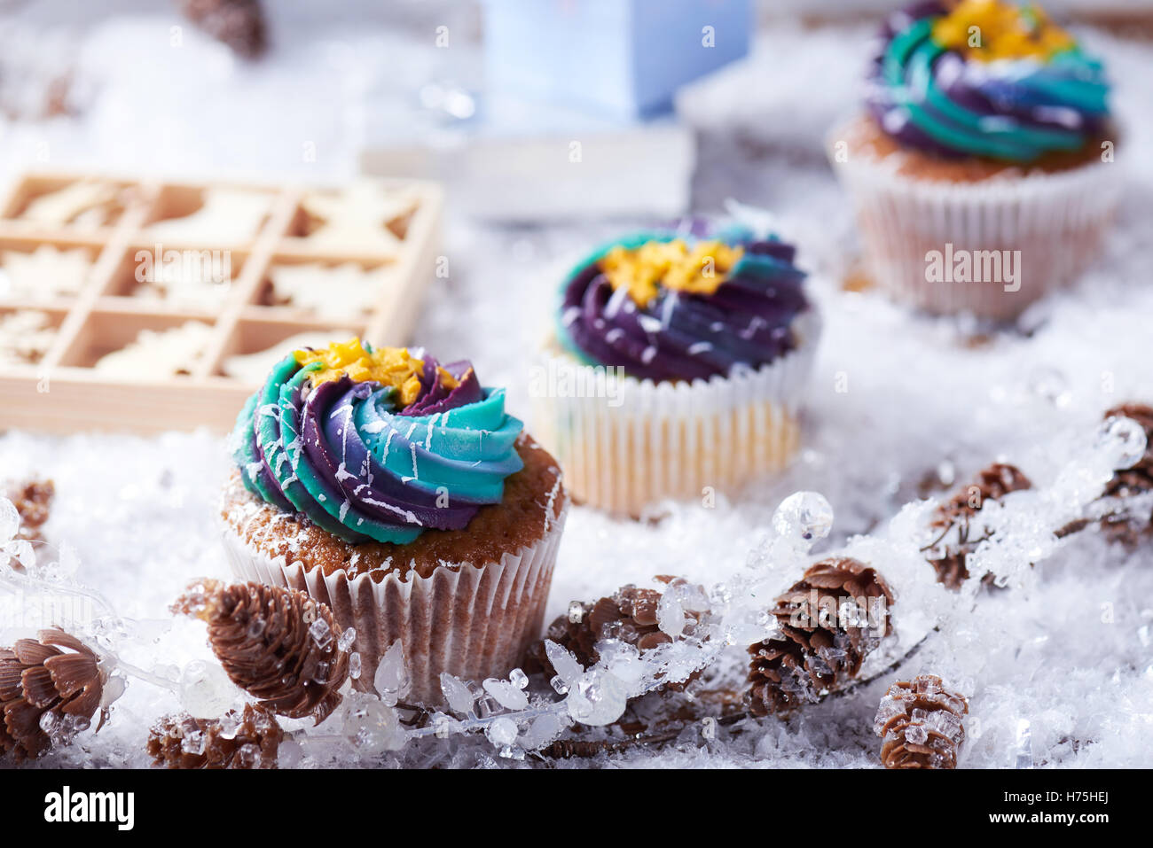 Winter cupcakes with gradient cream and golden stars on a snow with ...