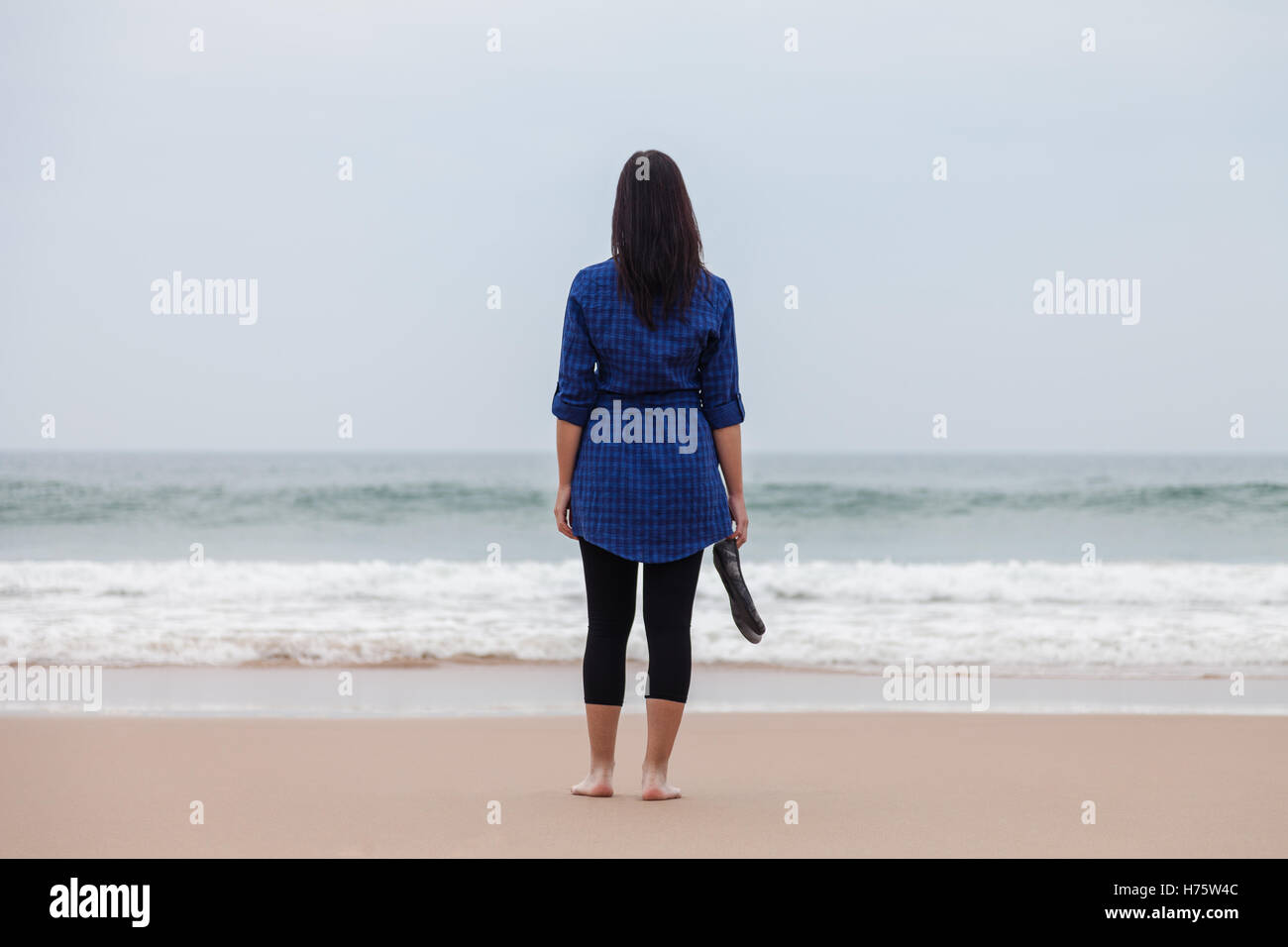Lonely and depressed woman standing in front of the sea in a deserted ...