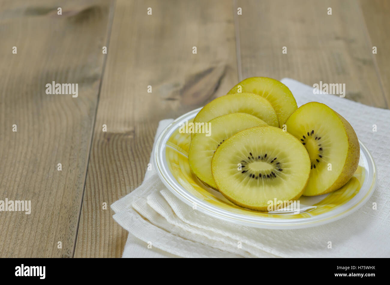 golden kiwi fruit and sliced on dish over wooden background Stock Photo ...