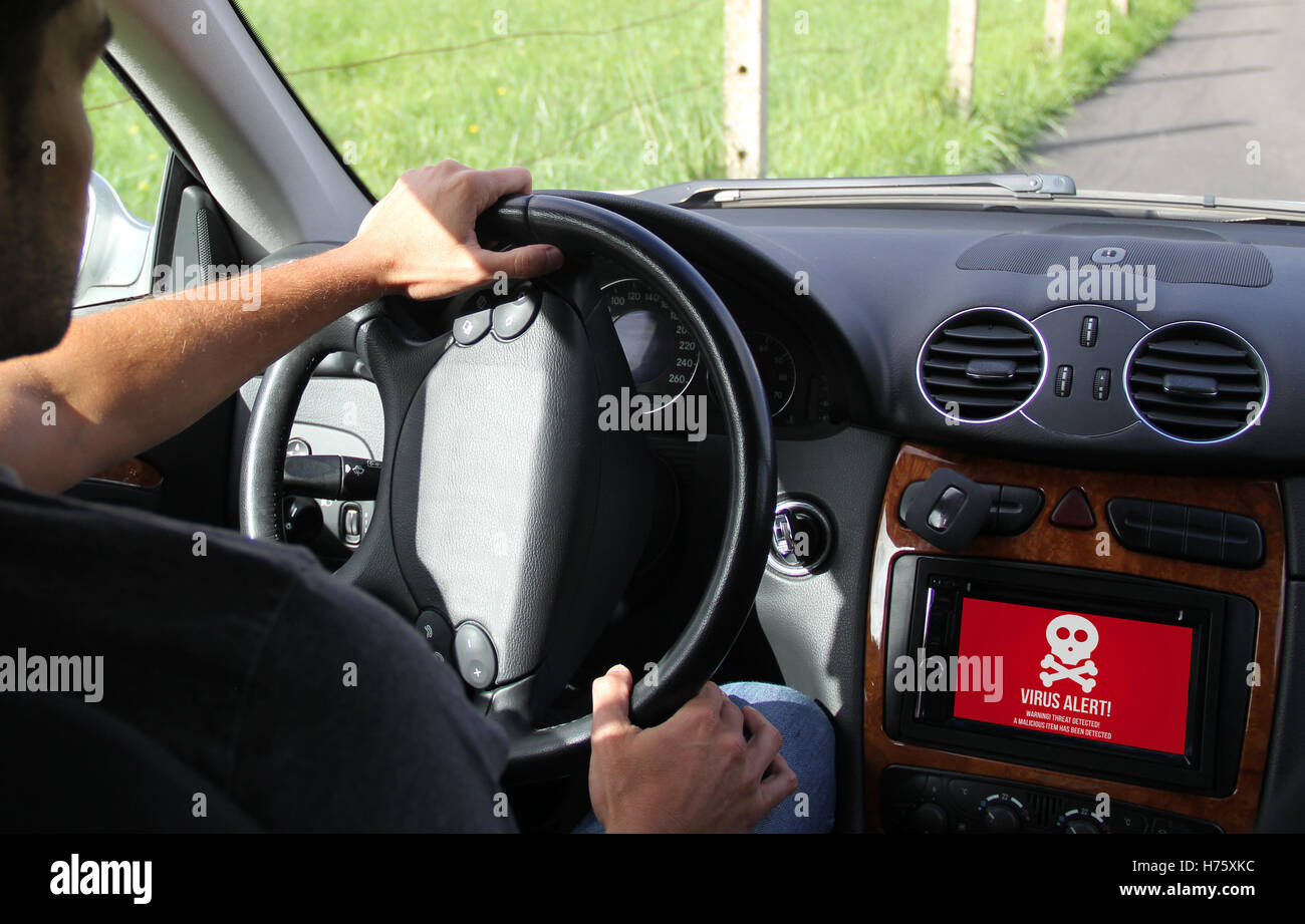 young man driving a hacked connected car showing on-board screen ...