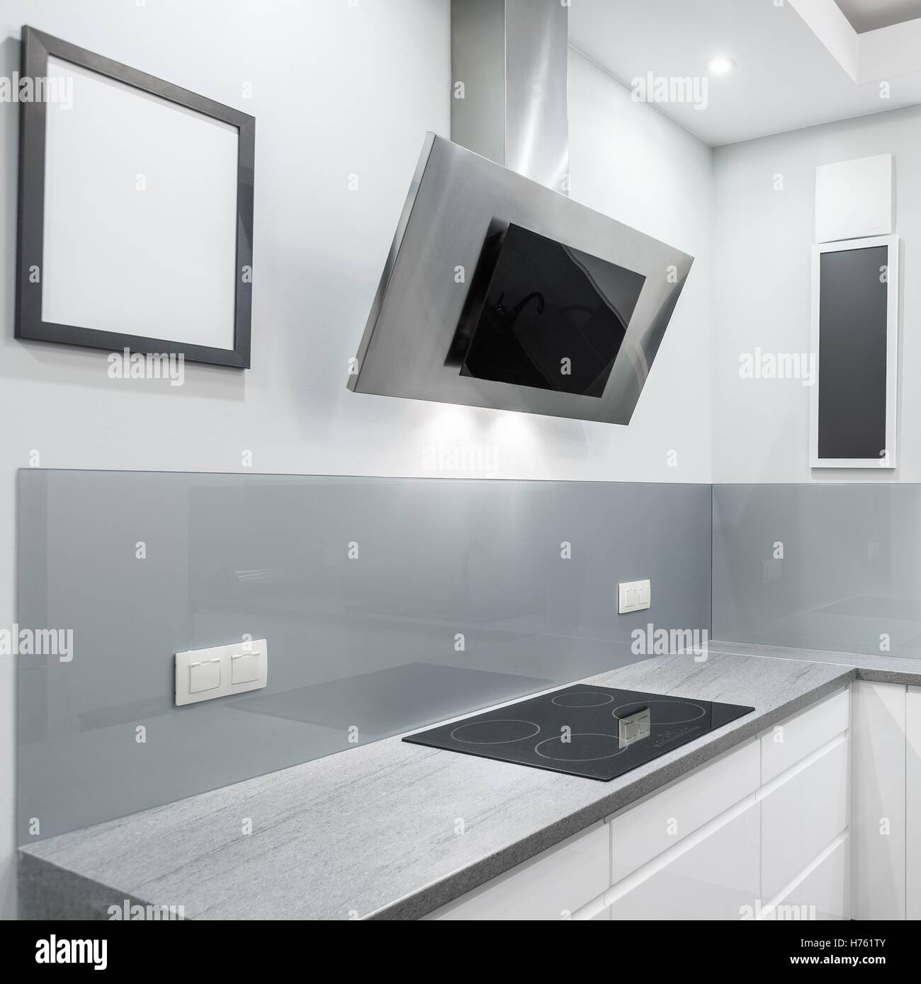 Kitchen with granite countertop, induction hob and steel exhaust hood ...