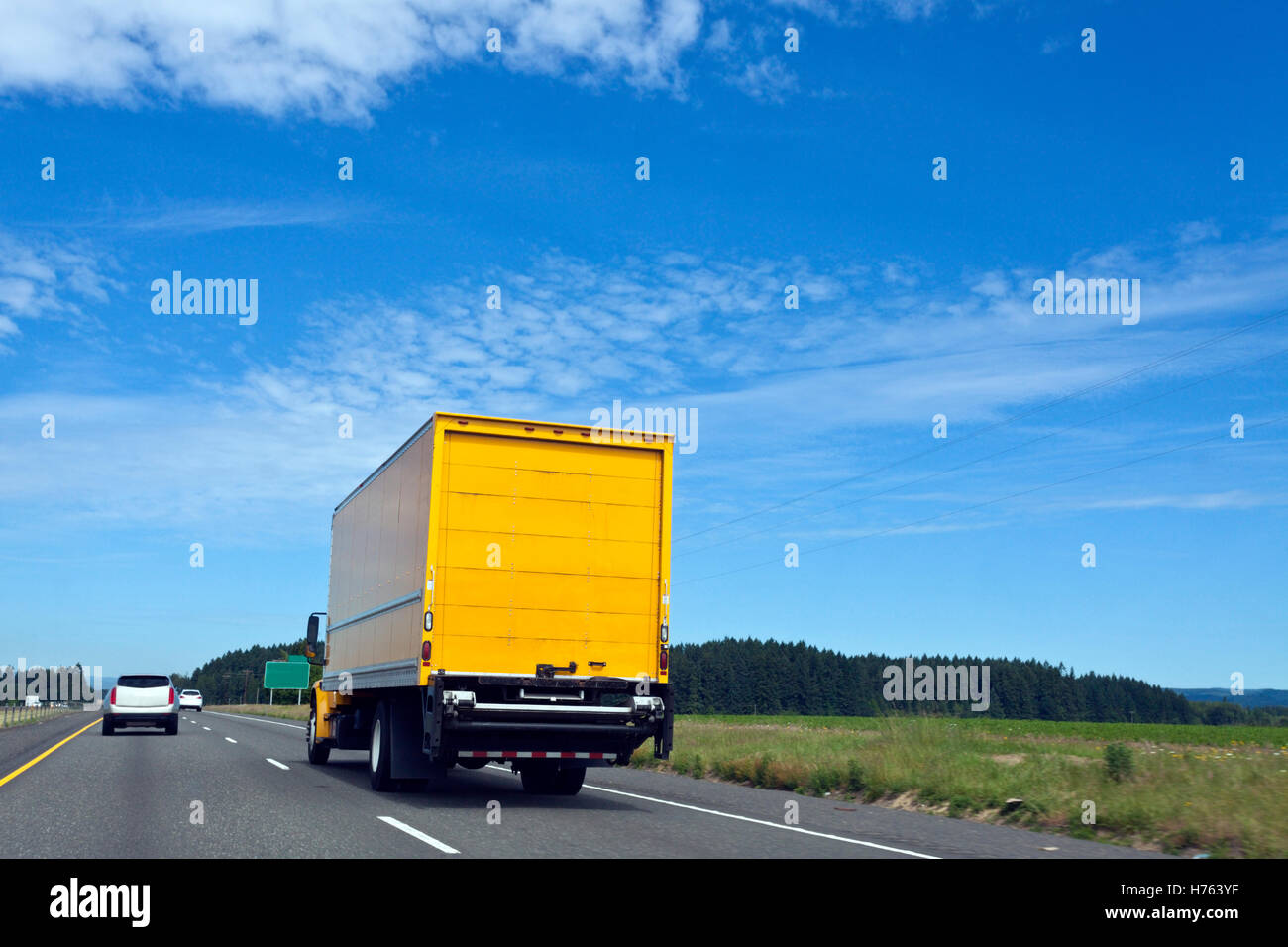 Yellow cargo freight truck on highway under blue sky Stock Photo - Alamy