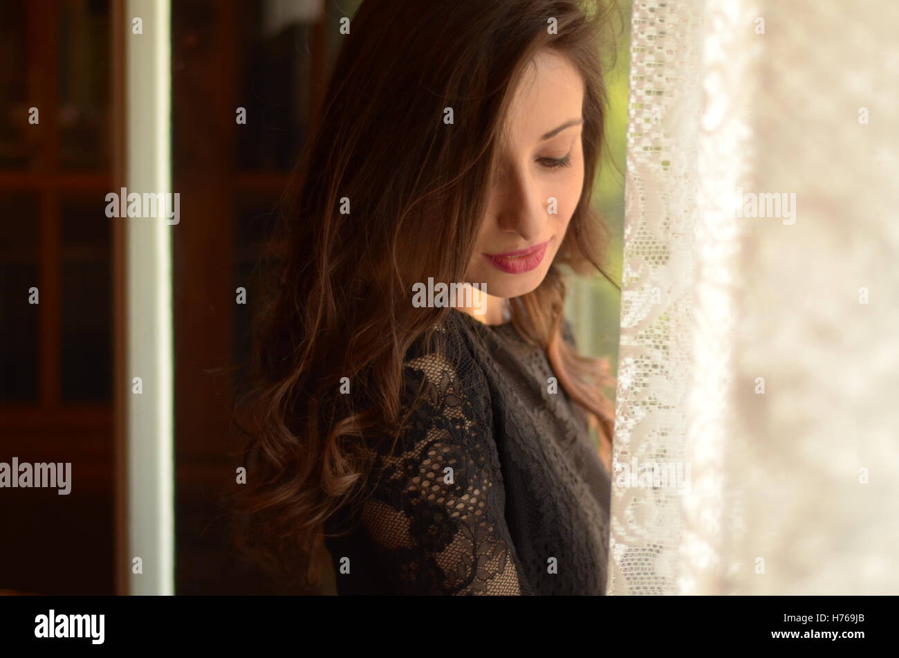 Woman standing by an open window Stock Photo - Alamy