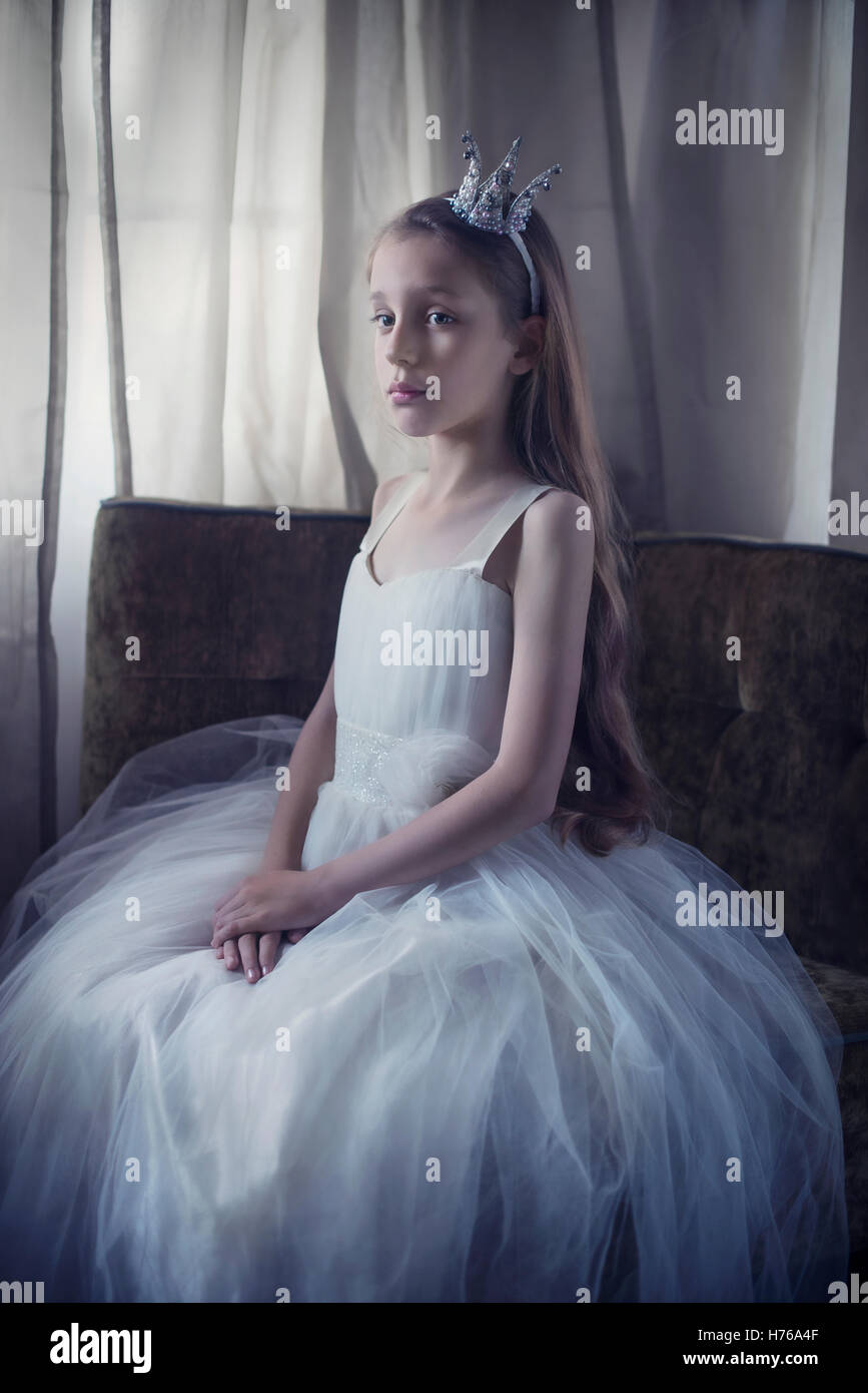 Portrait of a girl sitting on a chair dressed in a princess outfit ...