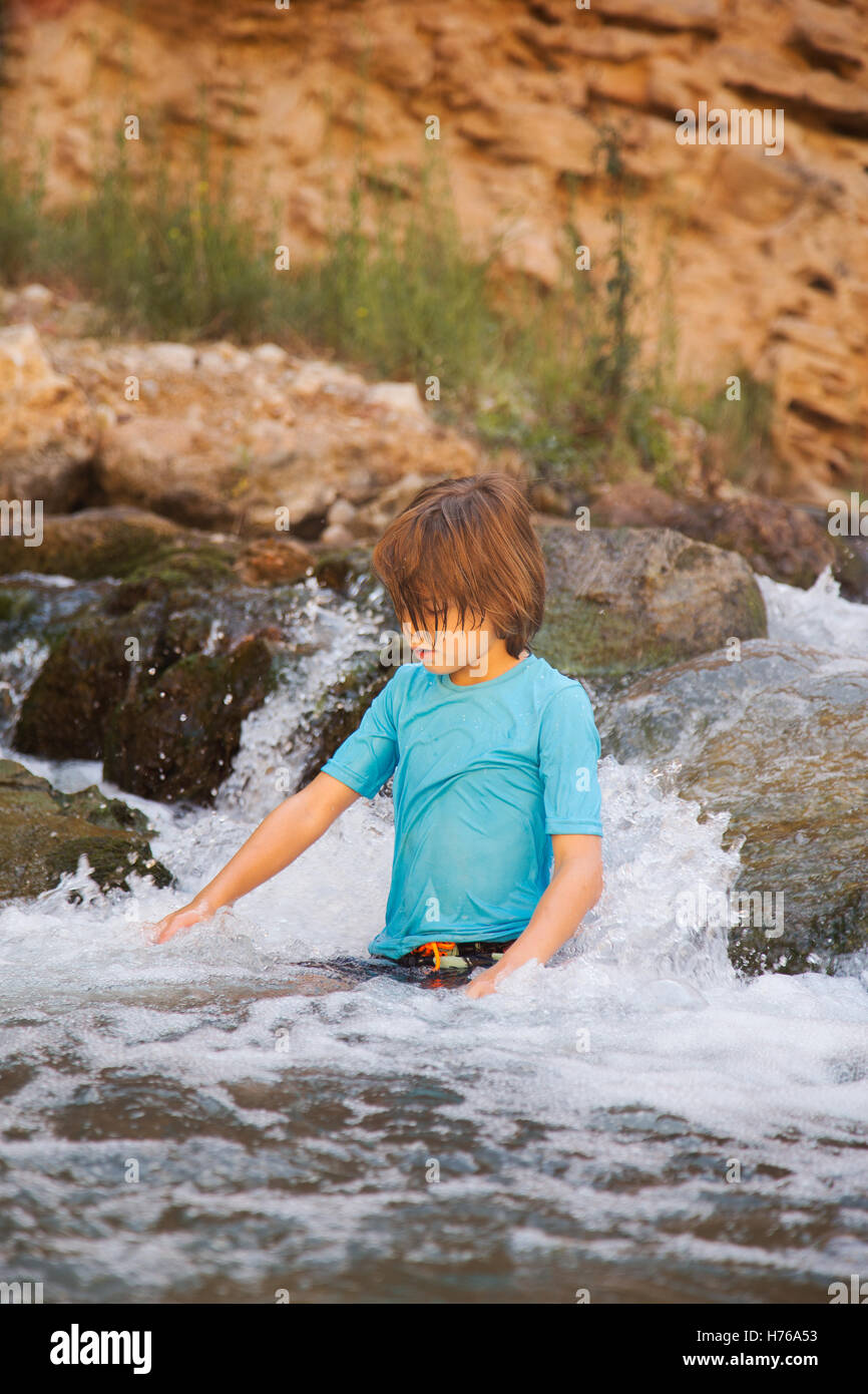 Boy sitting in a river Stock Photo - Alamy