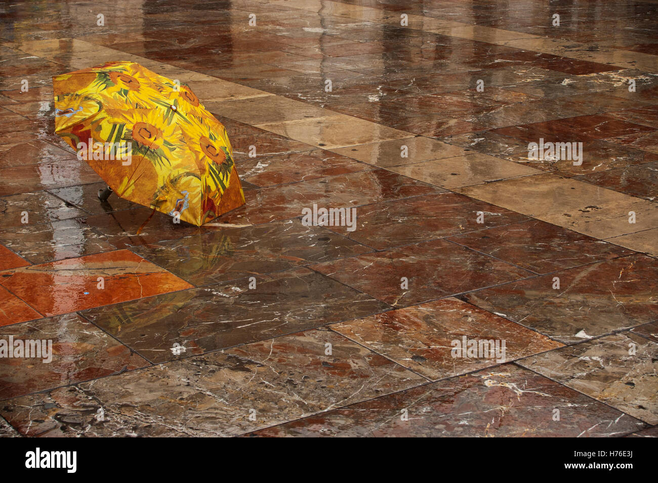 Open umbrella with floral pattern, on the rain-wet marble tile floor ...