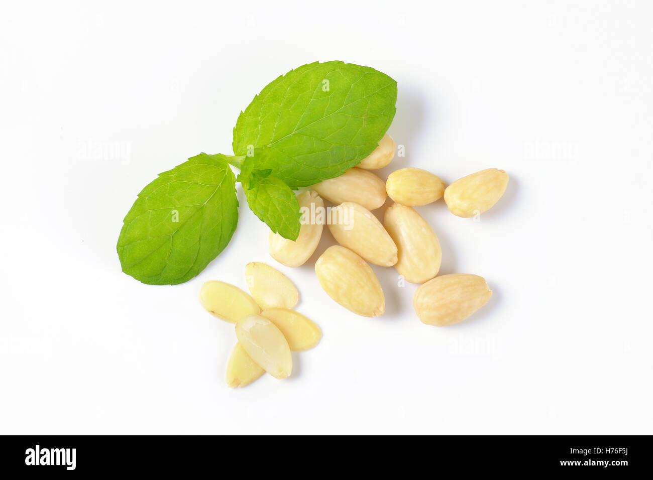 handful of sweet peeled almonds with fresh basil on white background ...