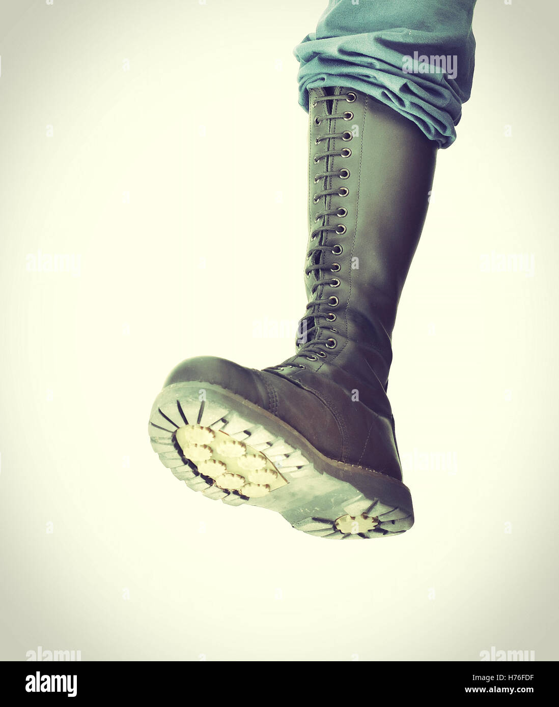 A tall lace-up combat boot stomping with the sole visible - vintage ...