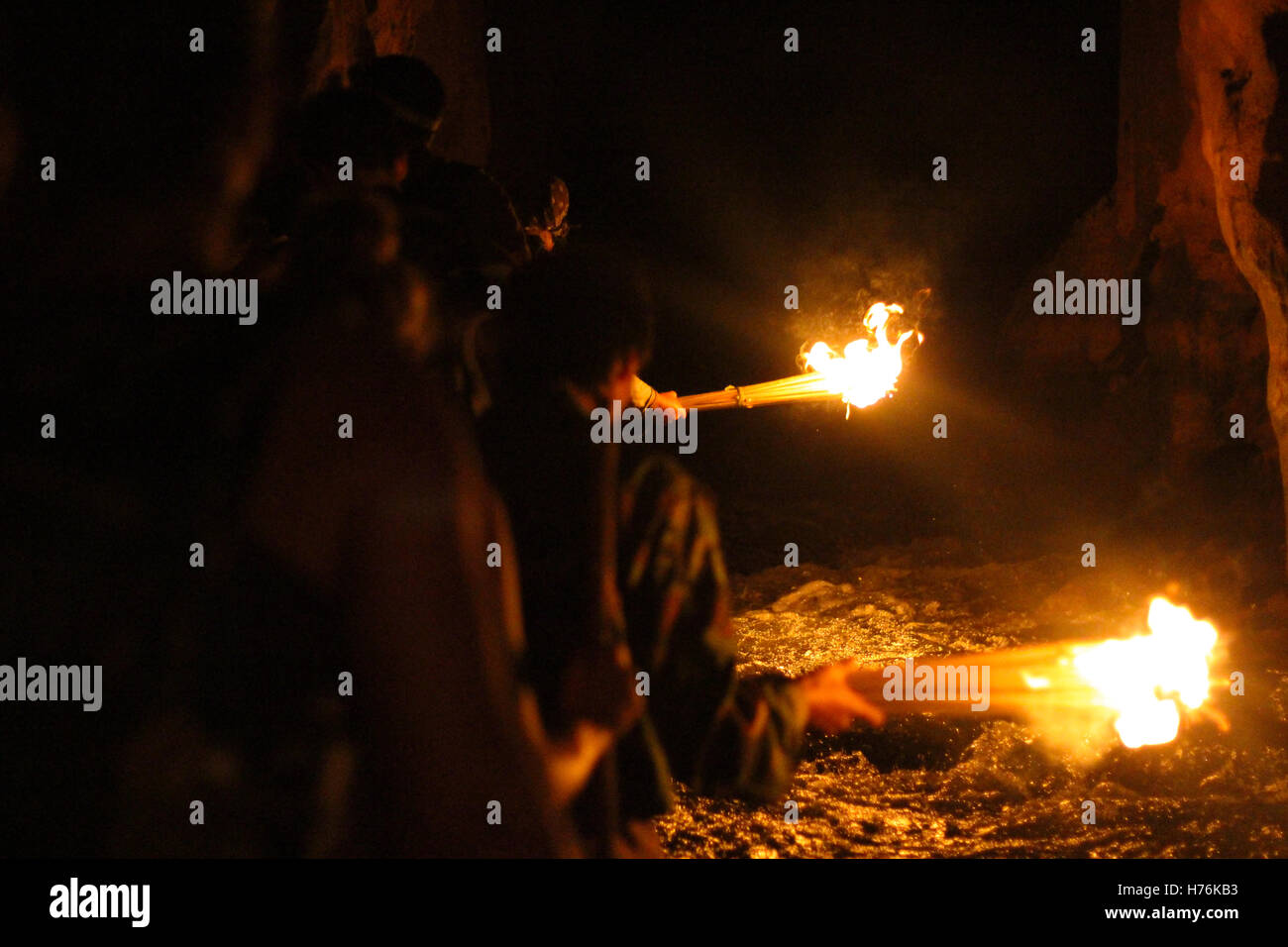A hiking group trek through a dark cave with only flaming torches for ...