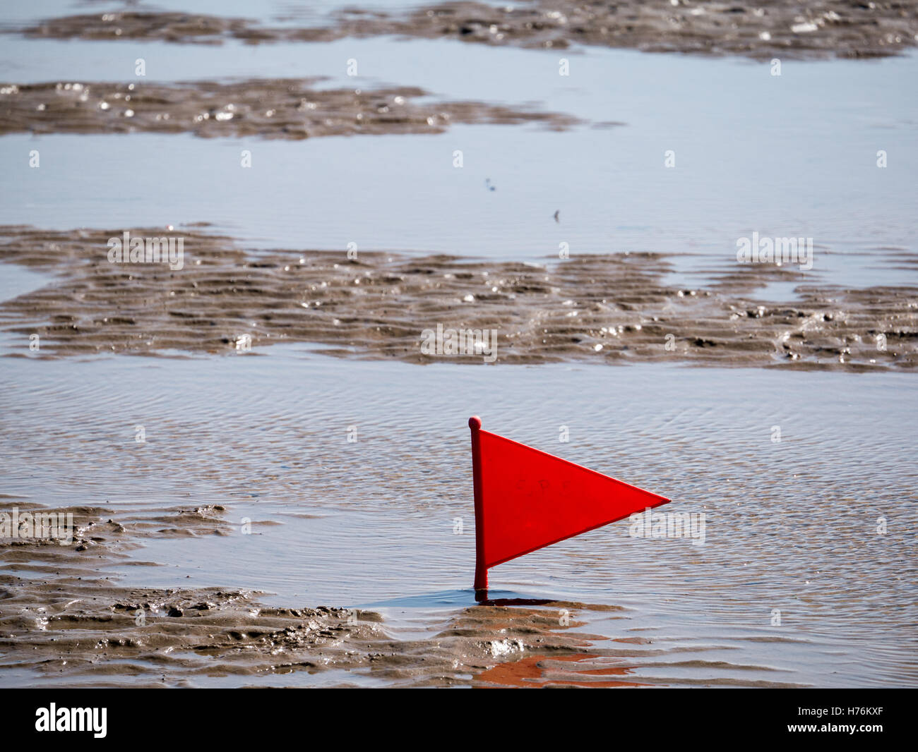 Triangular red flag in sand and mud bank Stock Photo - Alamy