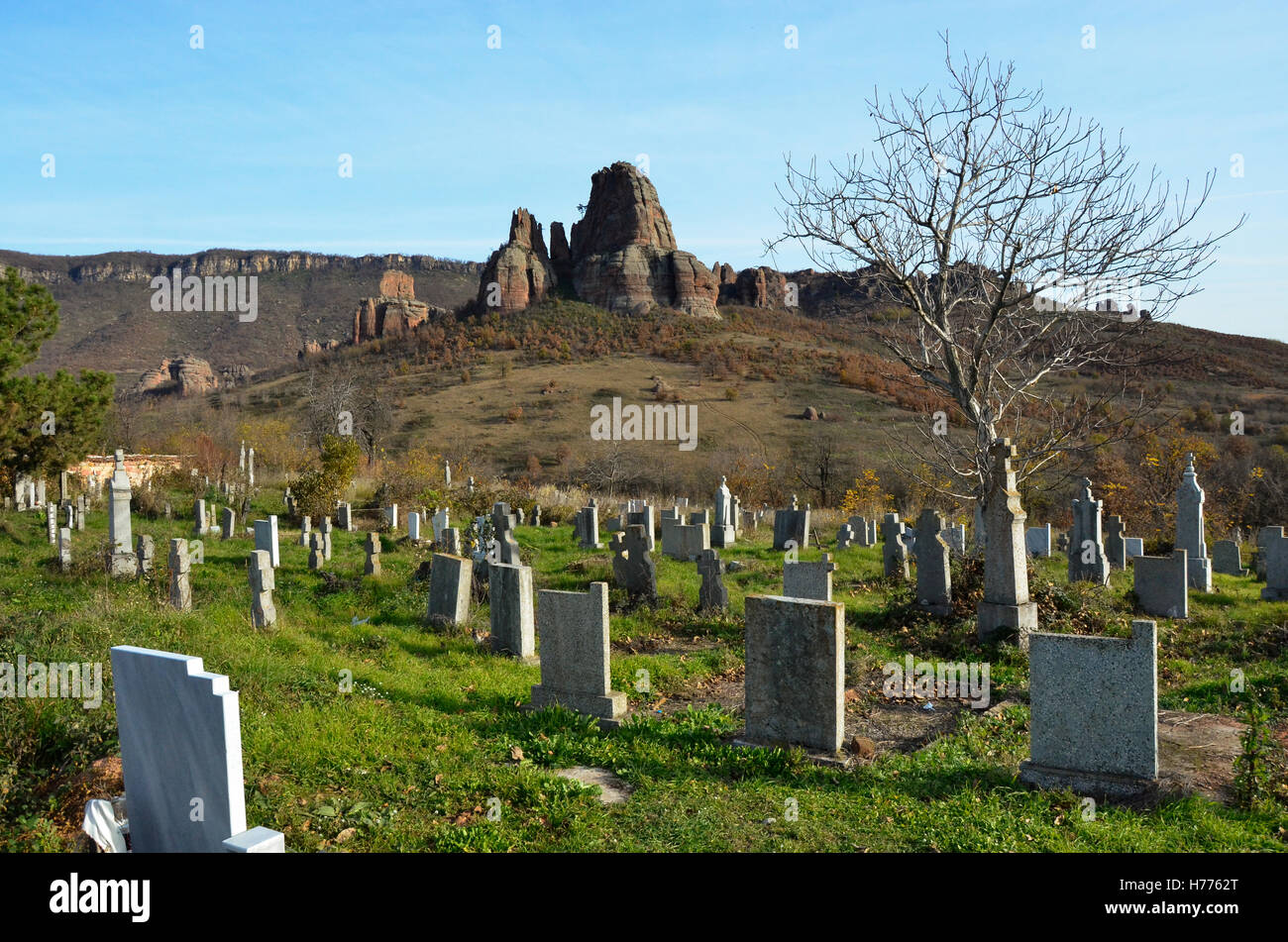 Graveyard and dead tree with rocky hill n background Stock Photo - Alamy