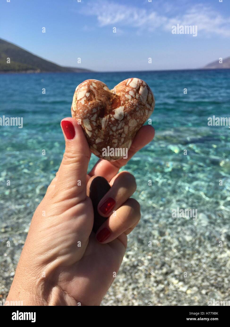 Woman's hand holding a heart shape pebble Stock Photo - Alamy