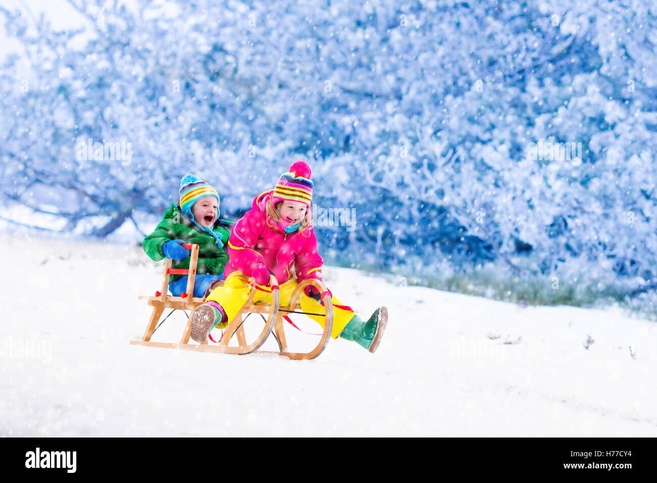 Little girl and boy enjoy a sleigh ride. Child sledding. Toddler kid ...