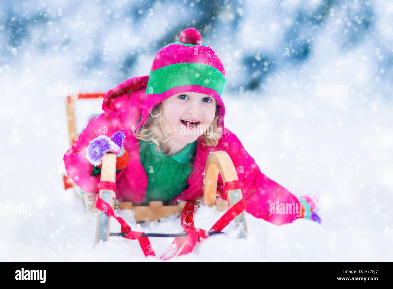 Little girl enjoying a sleigh ride. Child sledding. Toddler kid riding ...