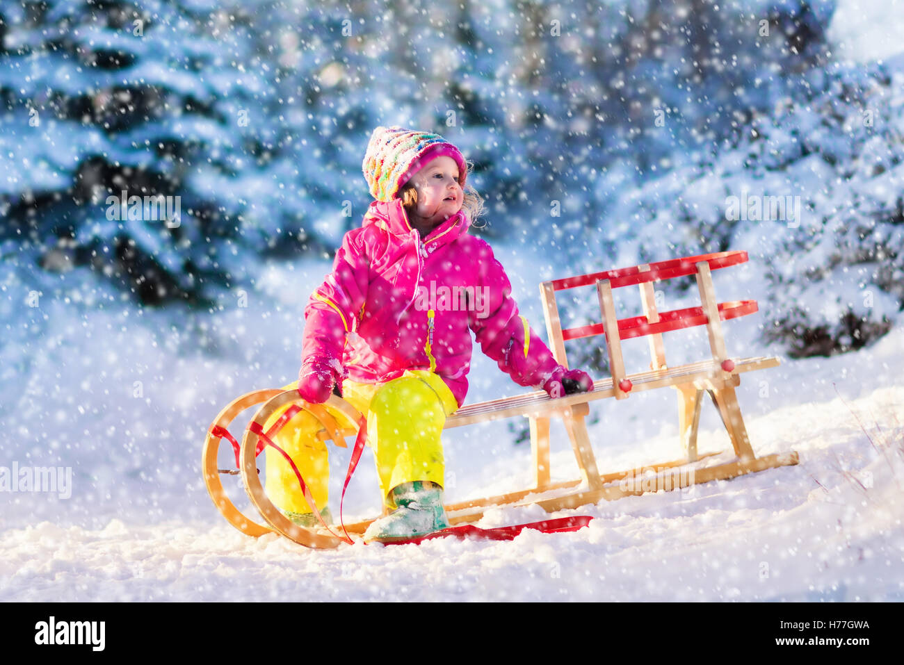 Little girl enjoying a sleigh ride. Child sledding. Toddler kid riding ...