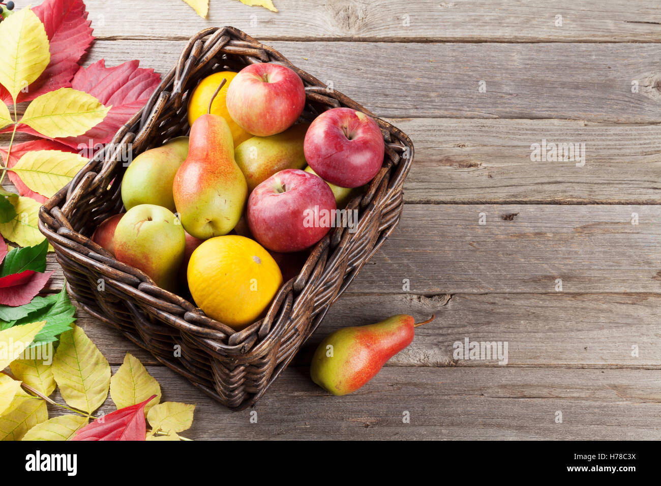 Autumn fruits box and colorful leaves on wooden table. View with copy ...