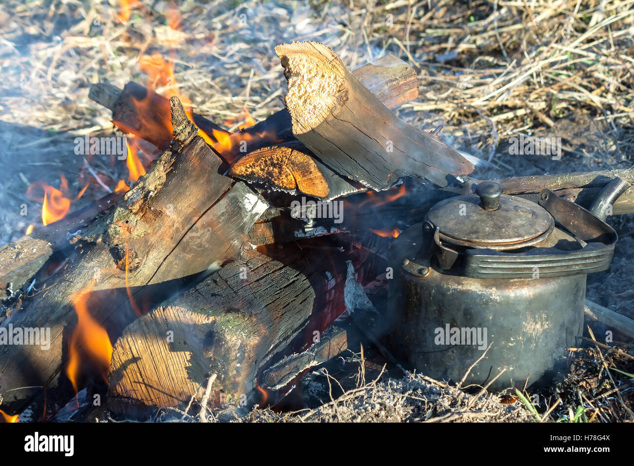 In a clearing lit a fire, near which heats a kettle of water Stock ...