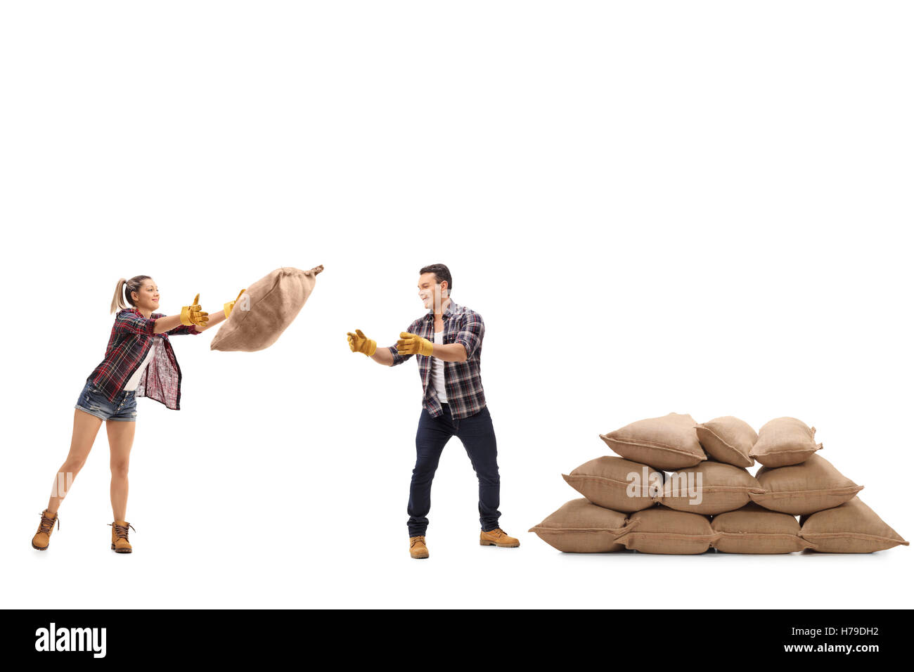 Female farmer throwing a burlap sack at a male farmer standing next to ...