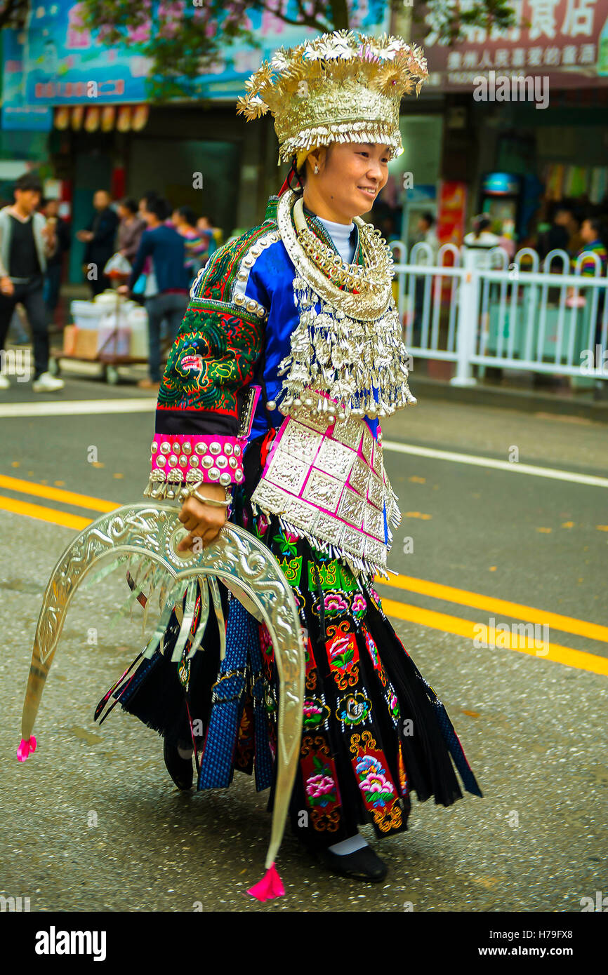 A girl in traditional Miao costume walks along a street of Taijiang ...