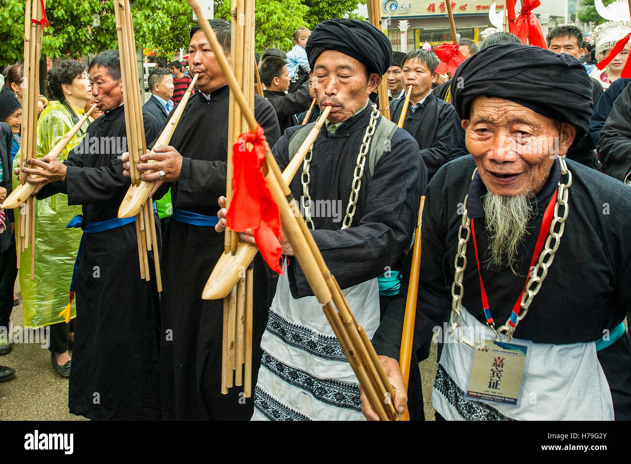 Men in traditional Miao costumes parade along the principal street of ...