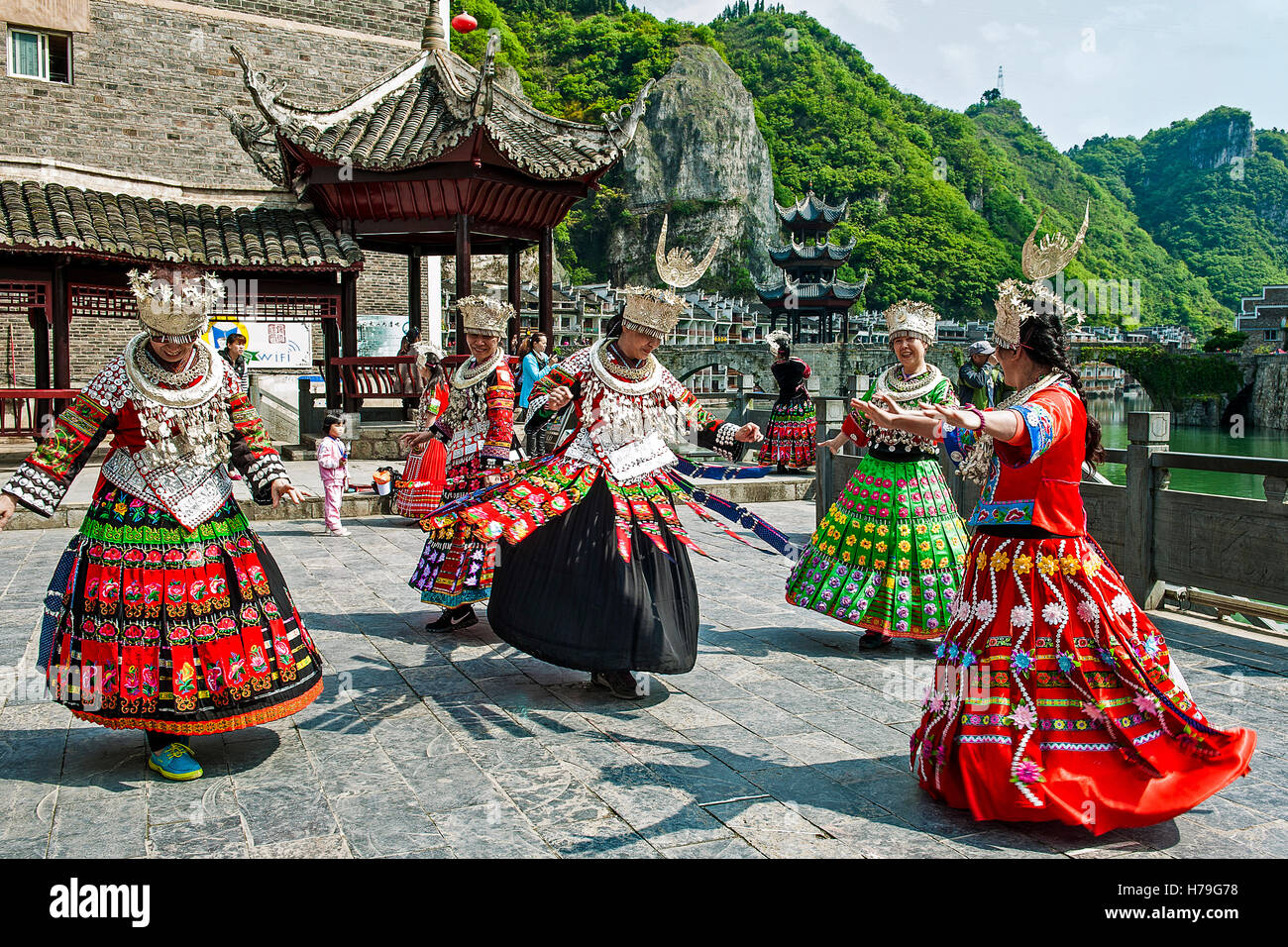 Women in typical Miao costumes dance in a place of Zhenyuan village ...