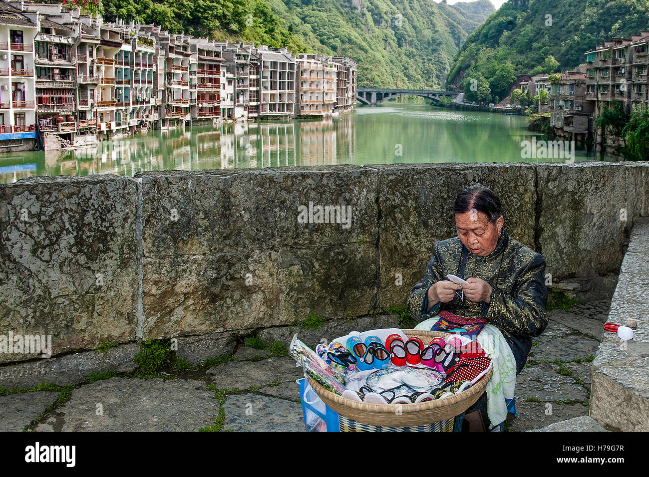 Old woman waves on the bridge with pagoda over Wuyang River in Zhenyuan ...